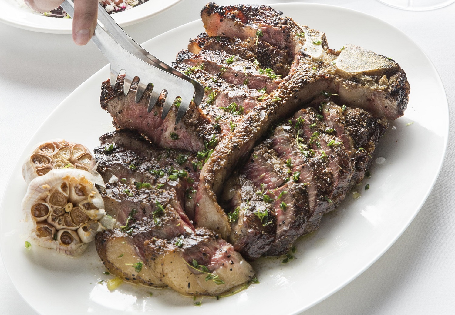 Sharing plates of Porterhouse steaks, crispy pork chop and more at this ...